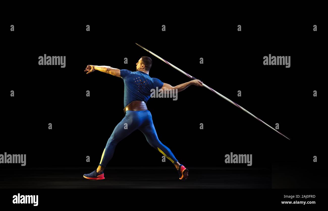 Male athlete practices in throwing javelin on black background in neon ...