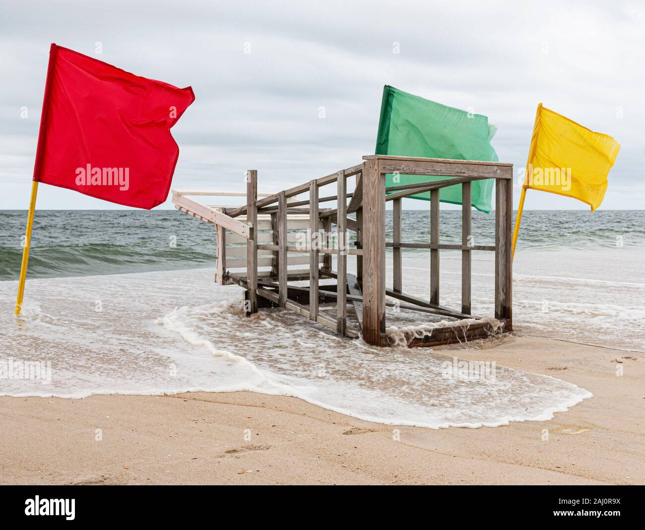 A lifeguard stand is lying down with red, green and yellow flags next ...