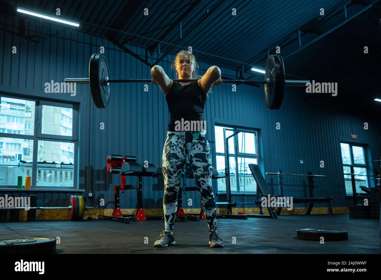 Caucasian teenage girl practicing in weightlifting in gym. Female ...