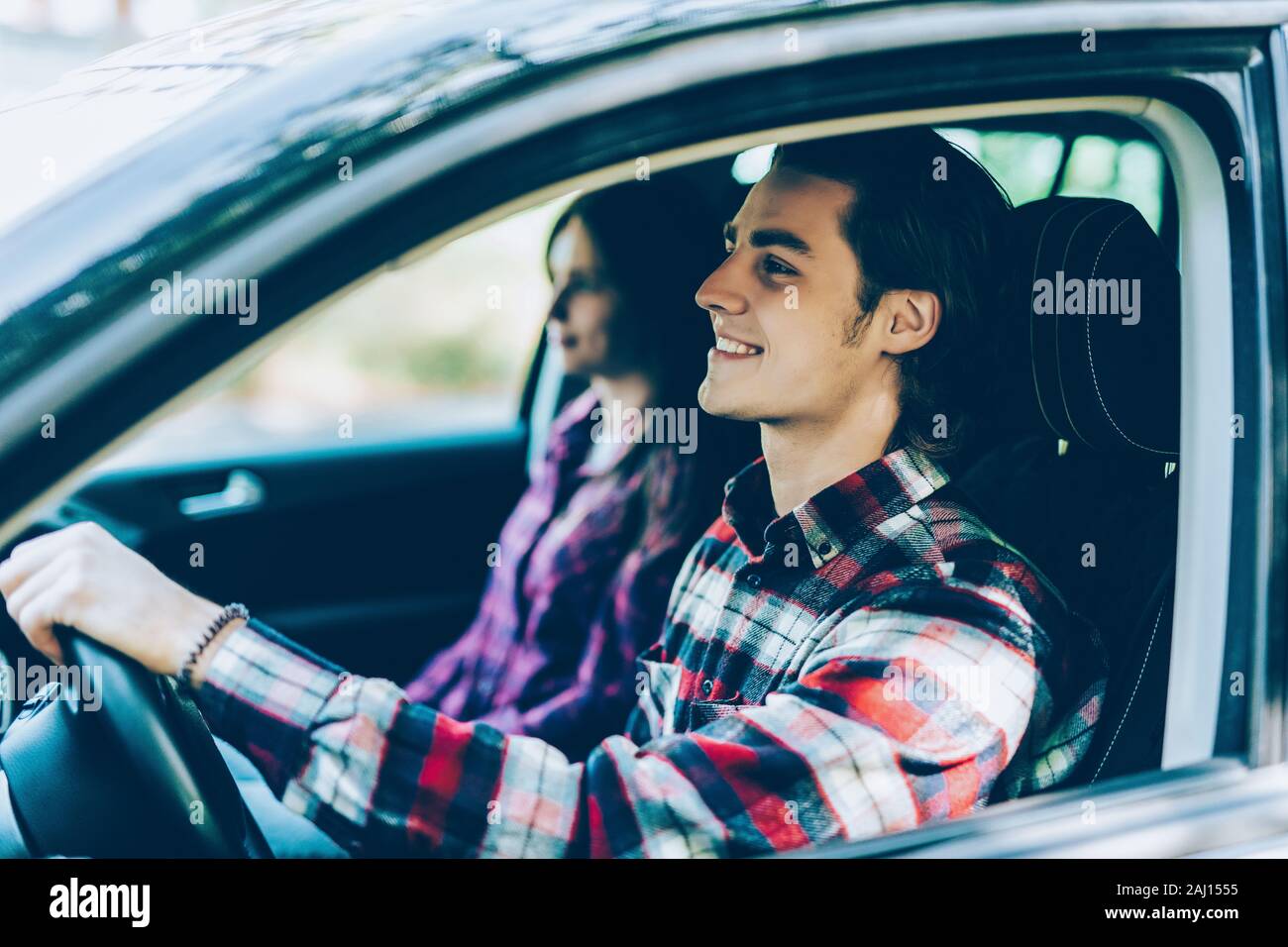 Romantic couple in their car going on a road trip. Young man driving ...