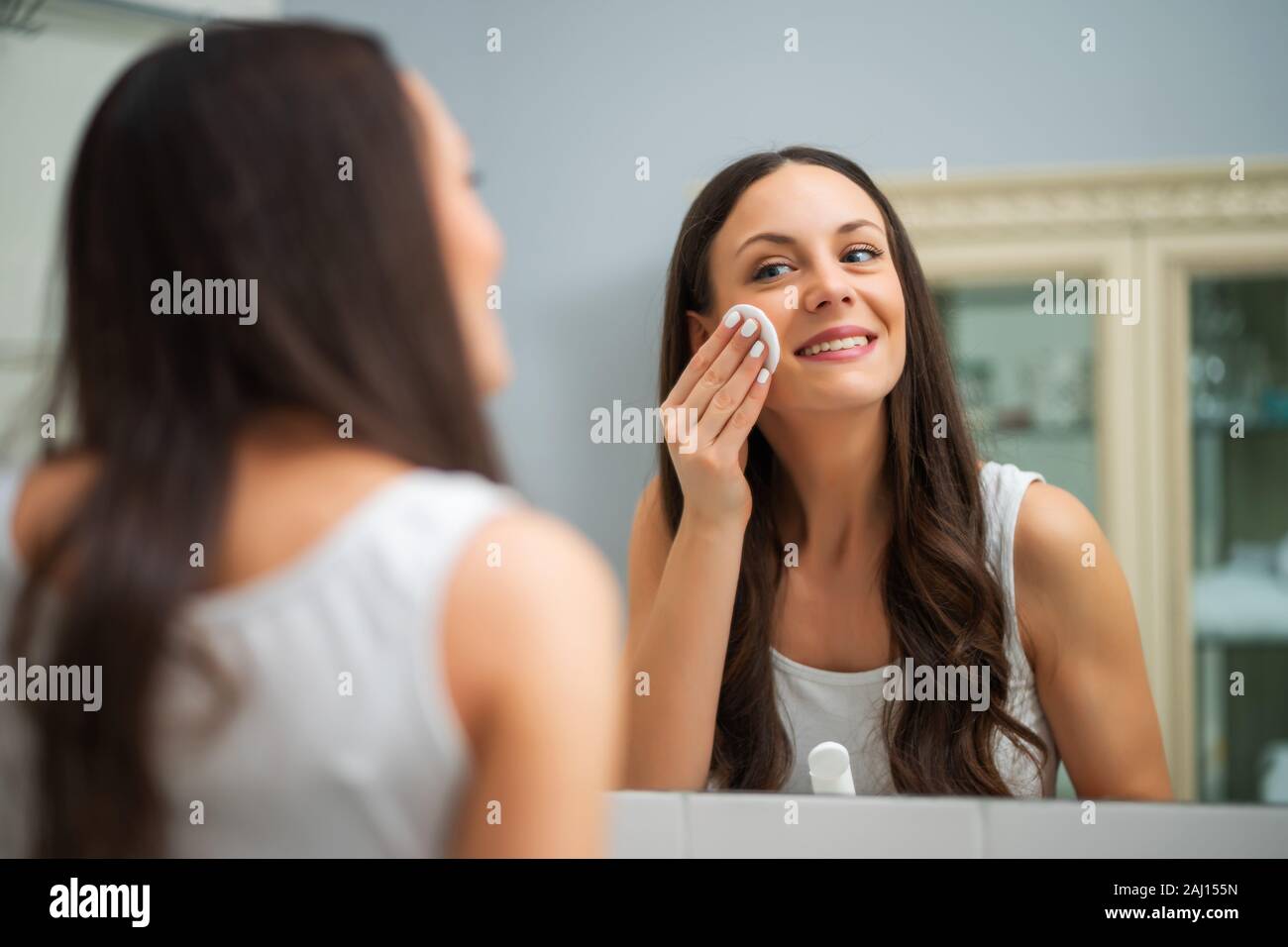 Portrait of young woman who is cleaning skin on her face Stock Photo ...