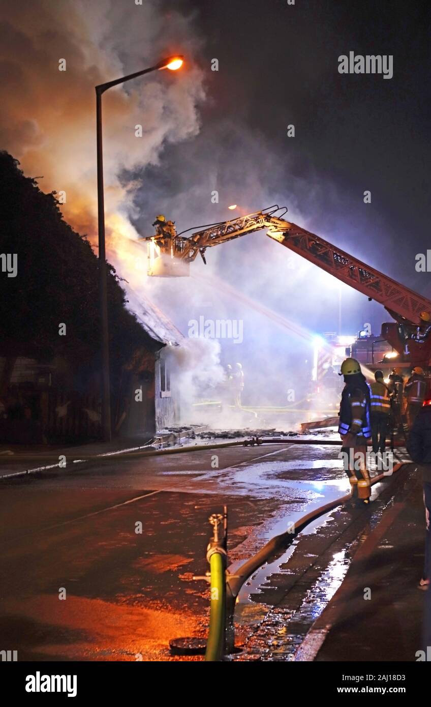 fiiremen fighting against a fire in the roof truss of a house at night ...