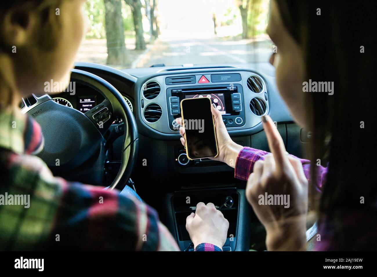 Back view of hands of young couple driving using navigation on mobile ...