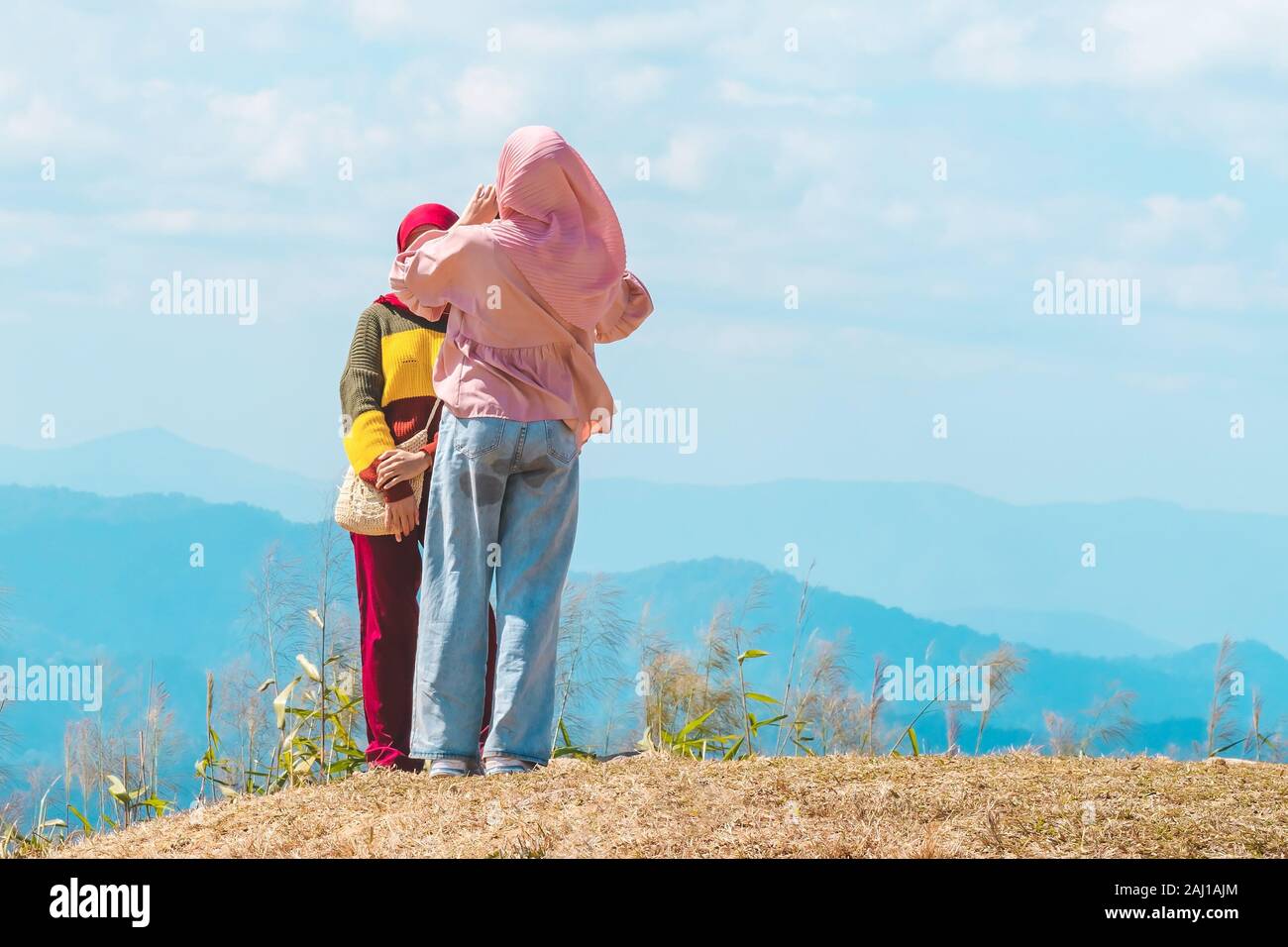 Back view of Muslim women wearing a Muslim dress and hijab enjoy on the ...