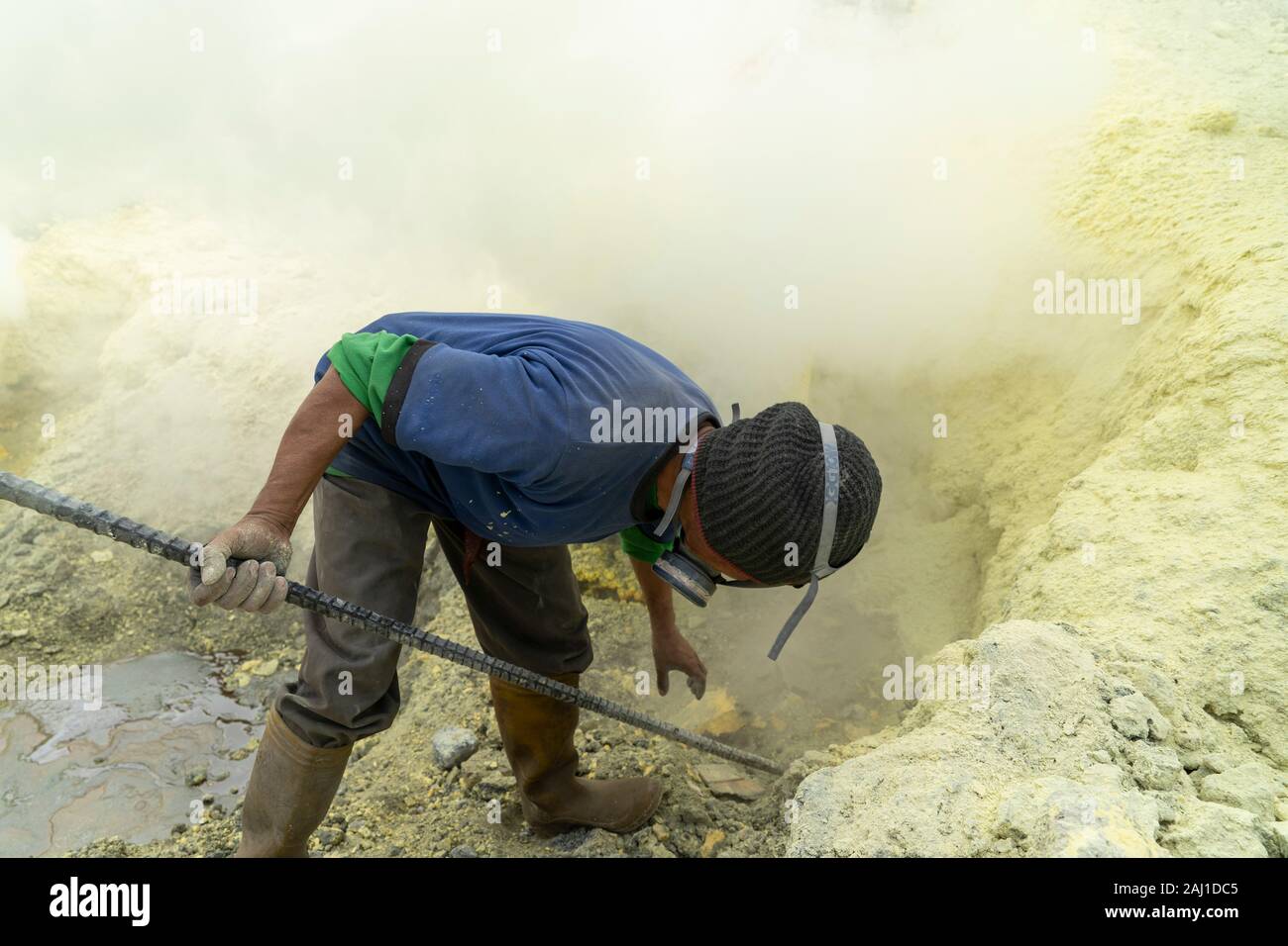 An Indonesian miner uses a crowbar to extract sulphur from a mine deep ...
