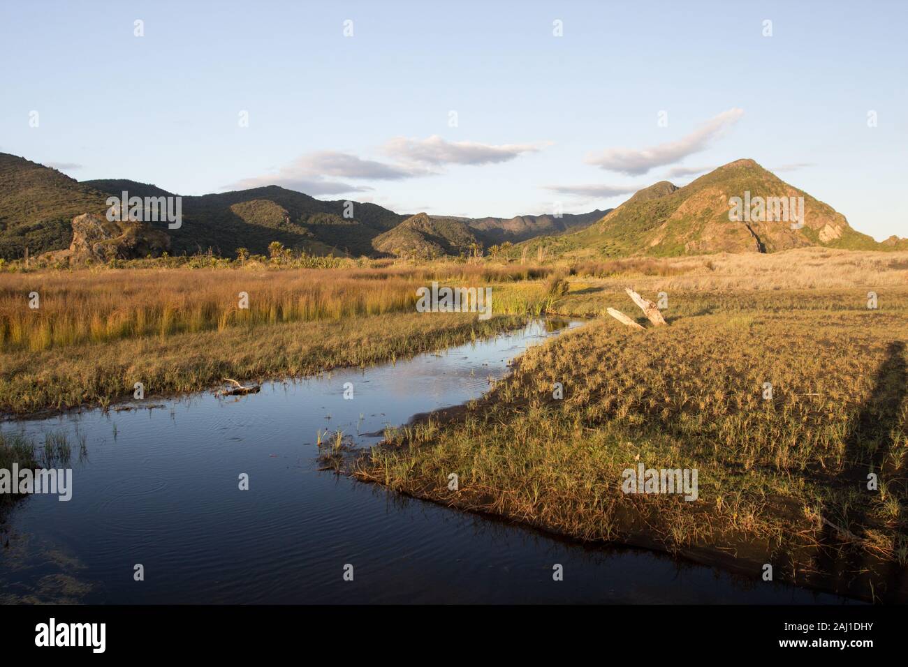 The Waitakere Ranges mountains reflected in the river at Whatipu Beach ...