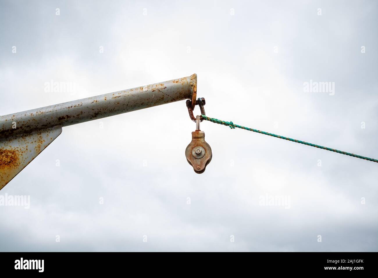 A pulley at the fishing dock with tension on rope against overcast sky ...
