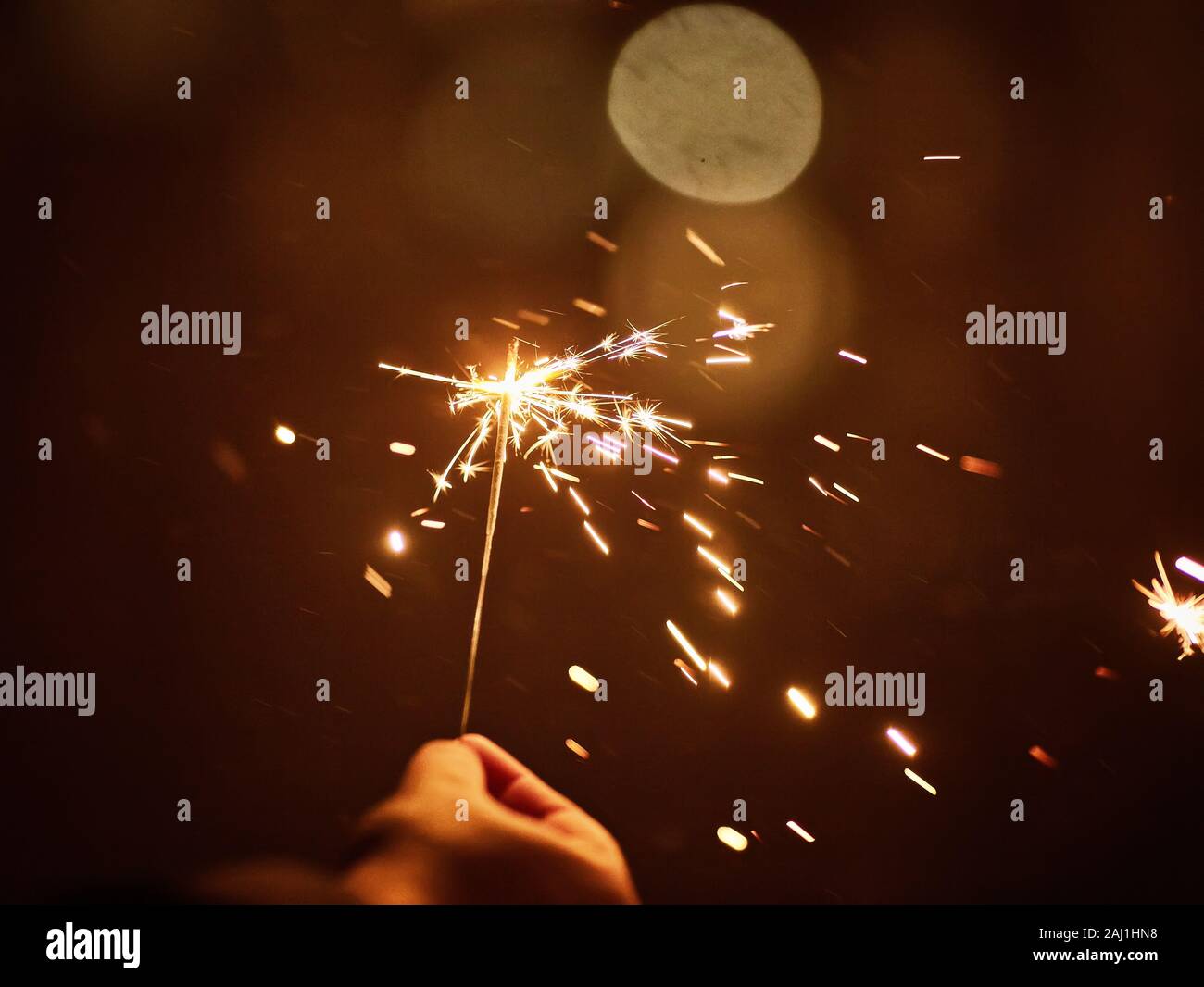 New year party burning sparkler closeup in female hand on black ...
