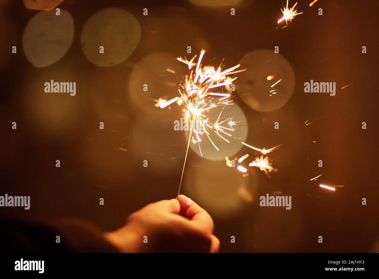 New year party burning sparkler closeup in female hand on black ...