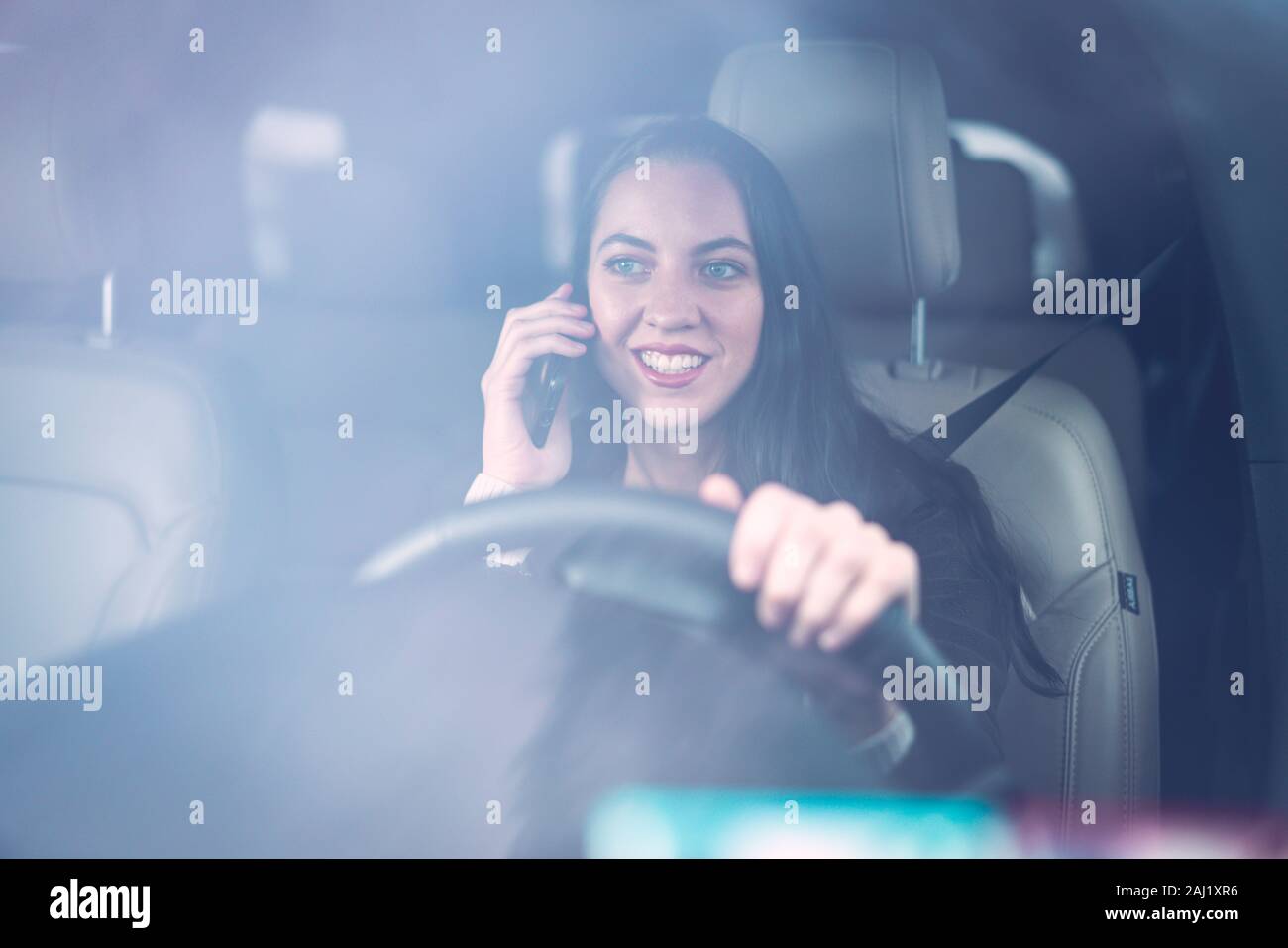 Young woman driving car talking on phone Stock Photo - Alamy