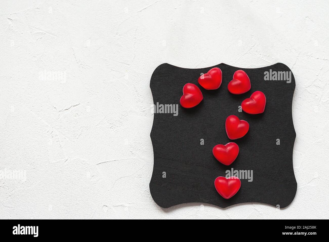 Question mark made of jelly hearts on a black board, white background ...