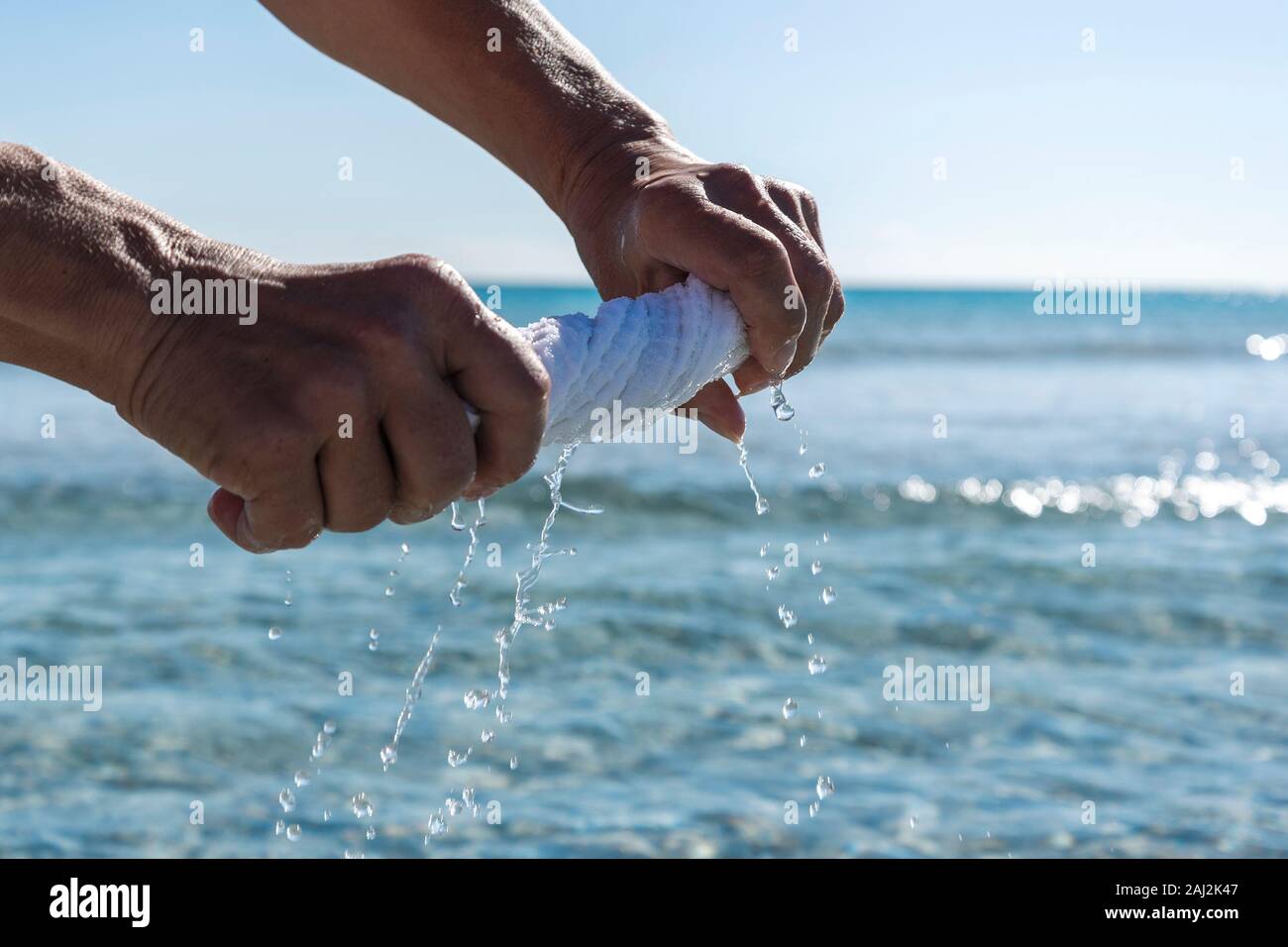 Hands squeeze wet cloth at sea Stock Photo - Alamy