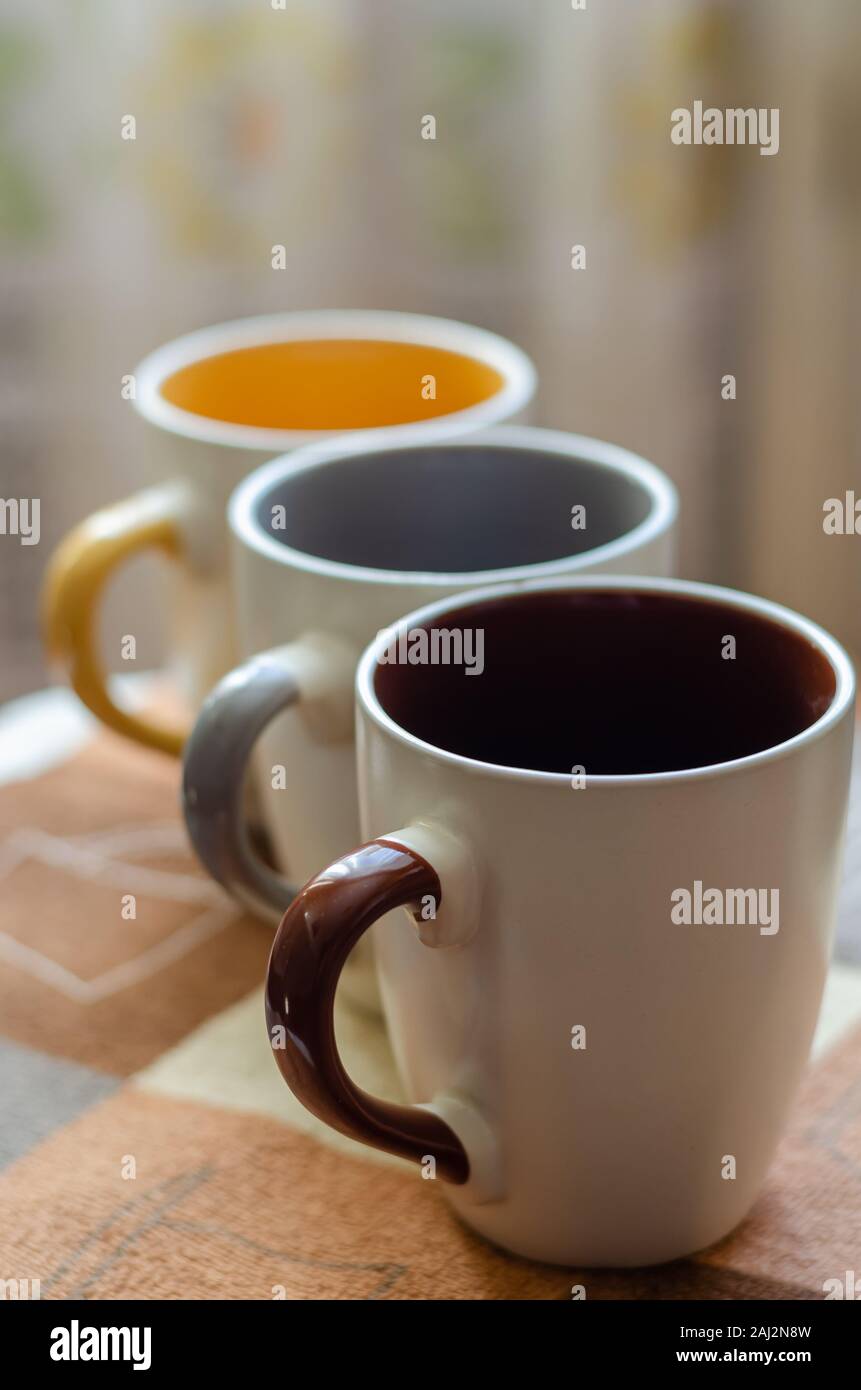 A set of ceramic cups of different colors for three family members. The ...