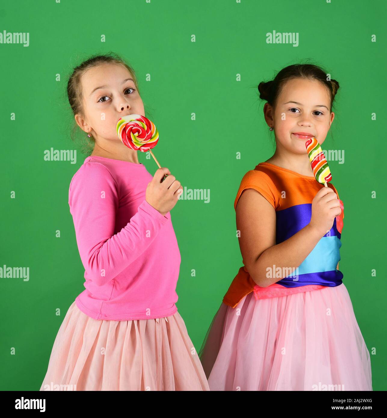 Happiness and dessert concept. Children eat big colorful sweet caramels ...