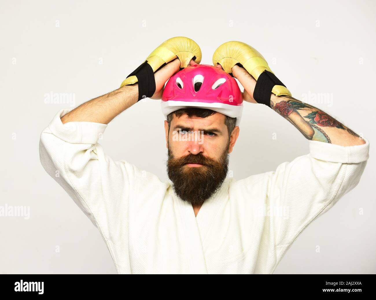 Karate man with suffering face in boxing gloves puts safety helmet on ...