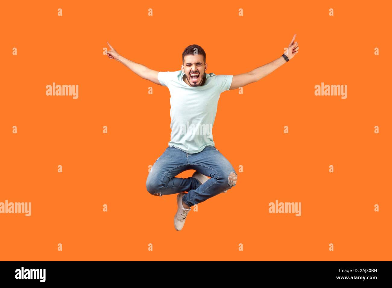 Full length of crazy overjoyed brunette man in white outfit jumping in ...