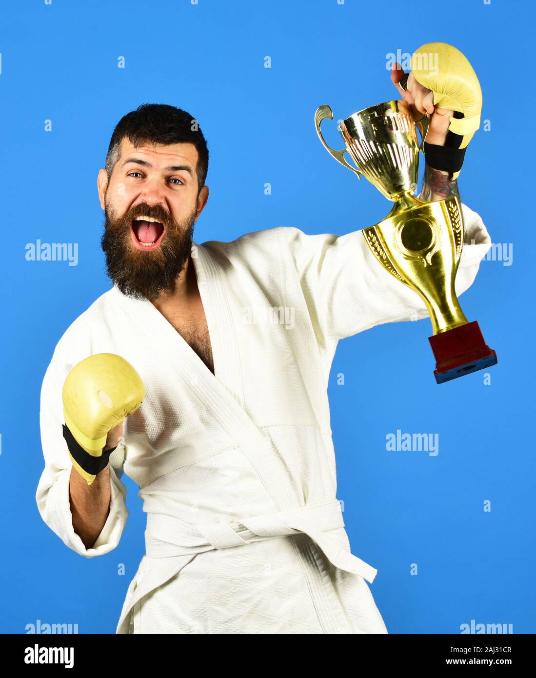 Karate man with cheerful face in boxing gloves says Yes holding gold ...