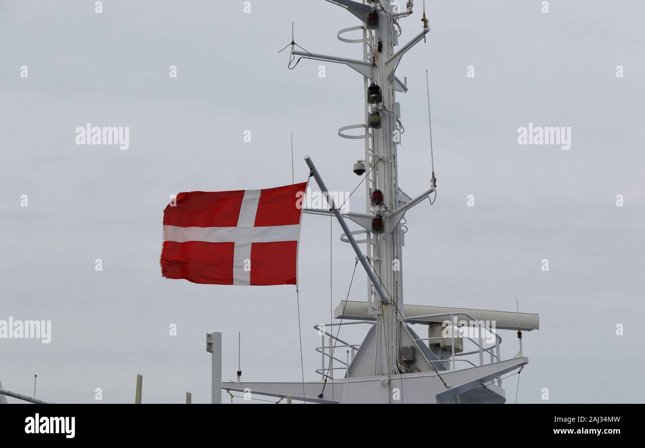Danish flag on a cruise ship mast tower flying in the wind over gloomy ...