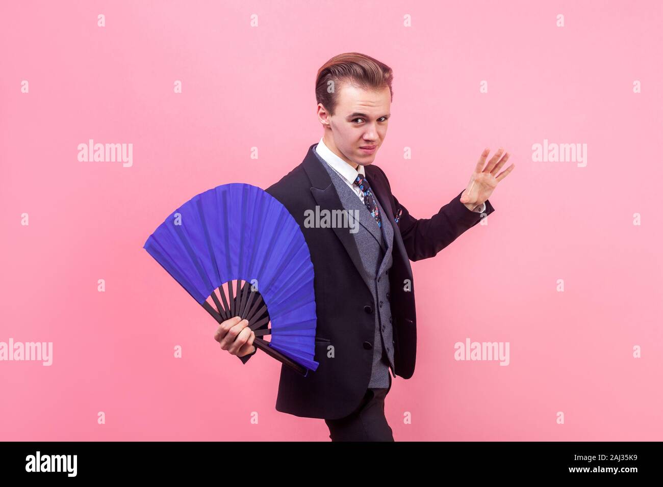 Portrait of serious concentrated young magician in tuxedo standing with ...