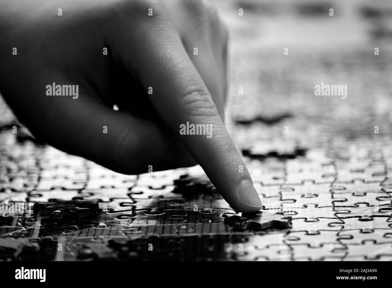Hand with finger completing a jigsaw puzzle for fun and achievement ...