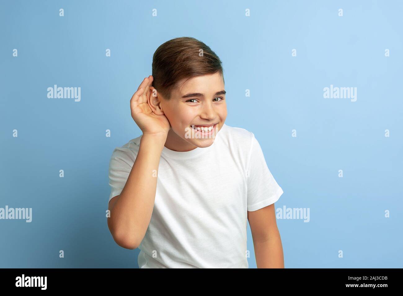 Listening attented, smiling. Caucasian boy portrait isolated on blue ...