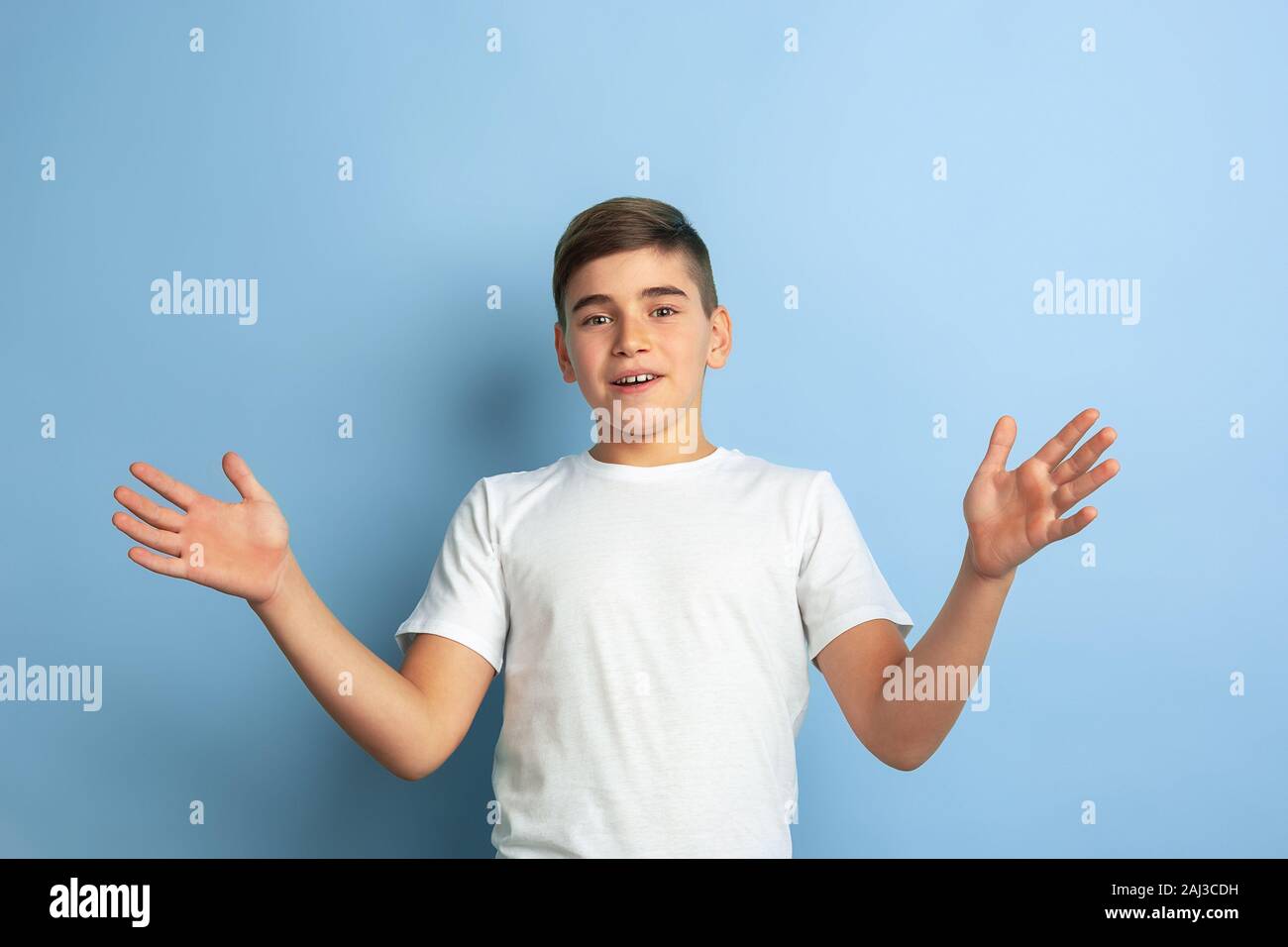 Greeting gesture, wondered. Caucasian boy portrait isolated on blue ...