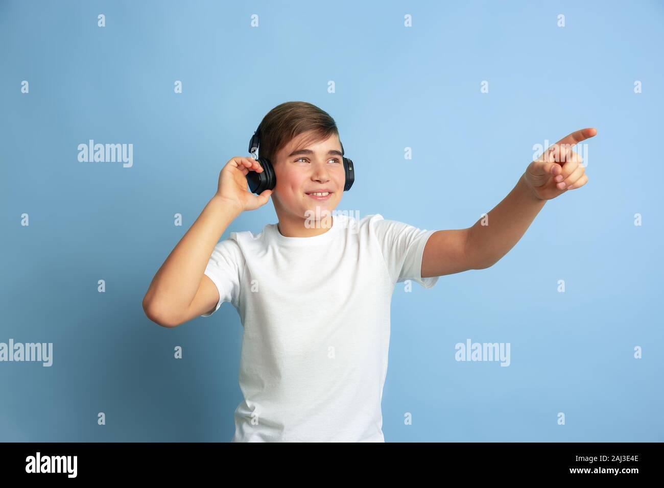 Listen to music, pointing at side. Caucasian boy portrait isolated on ...