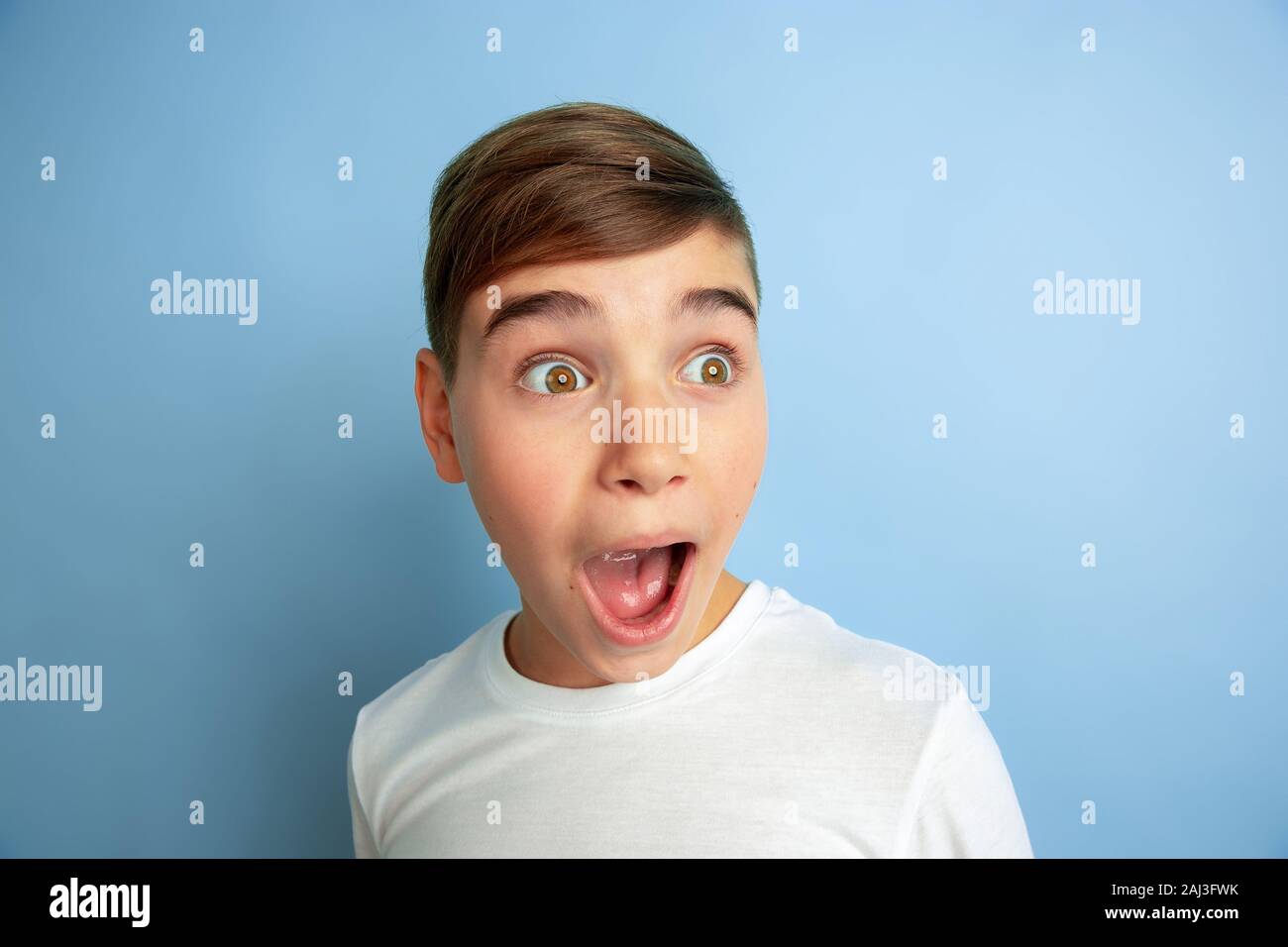 Shocked screaming. Close up. Caucasian boy portrait isolated on blue ...