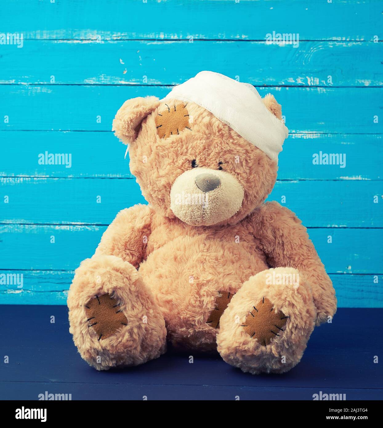 sad brown bear sits with bandaged white medical bandage head, injury ...
