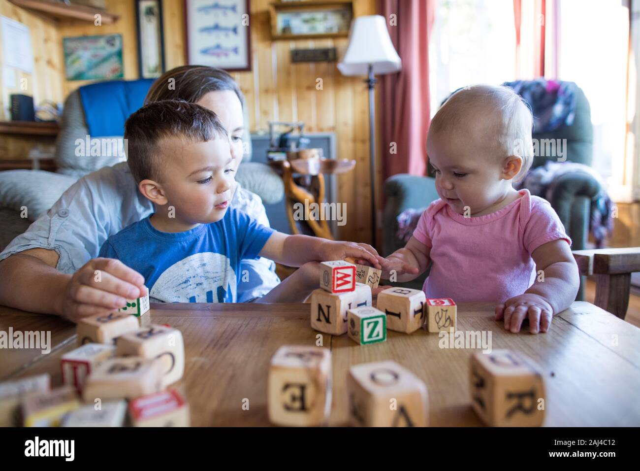 Mother helping her two children play nicely together Stock Photo - Alamy