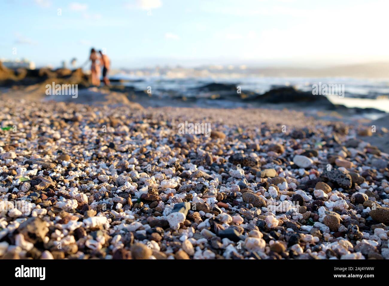 Pebbly beach in late afternoon with warm sunshine light and blurred ...