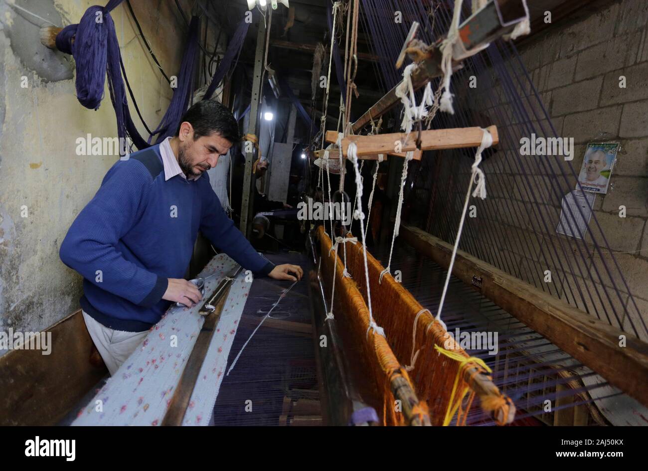 A Palestinian worker weaves carpets on a traditional wooden loom at a ...