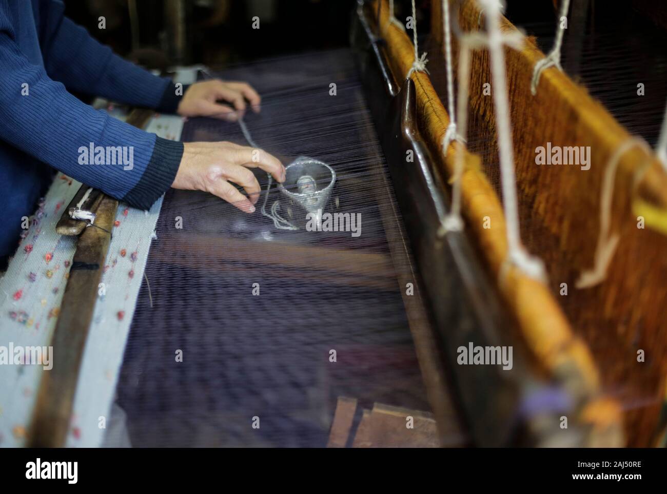A Palestinian worker weaves carpets on a traditional wooden loom at a ...