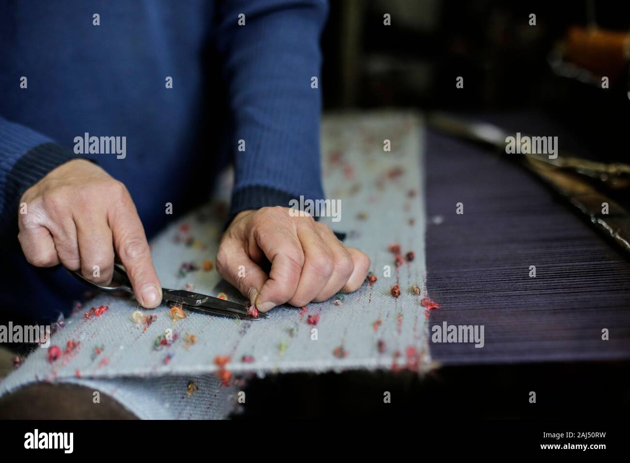 A Palestinian worker weaves carpets on a traditional wooden loom at a ...
