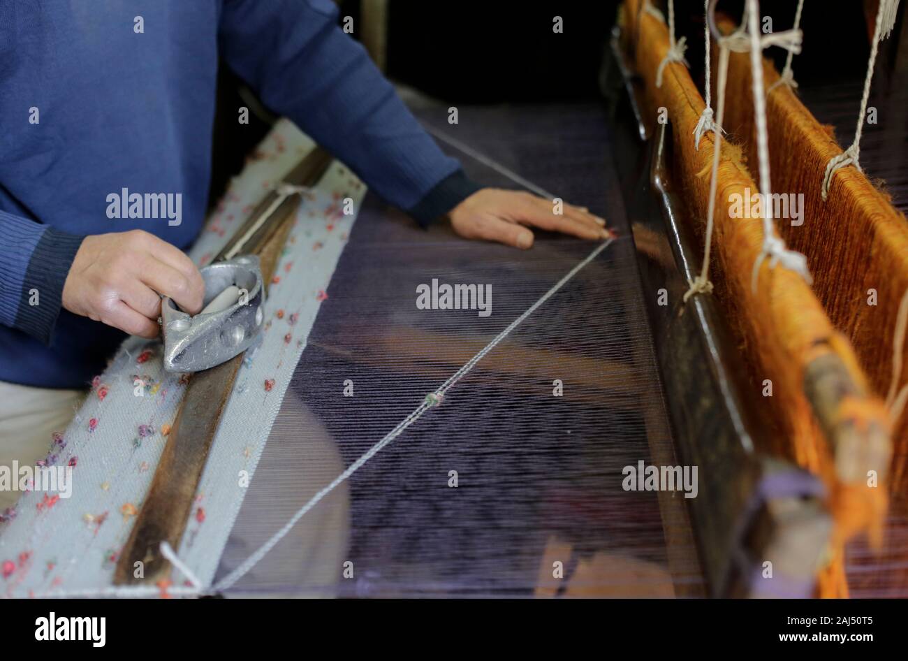 A Palestinian worker weaves carpets on a traditional wooden loom at a ...