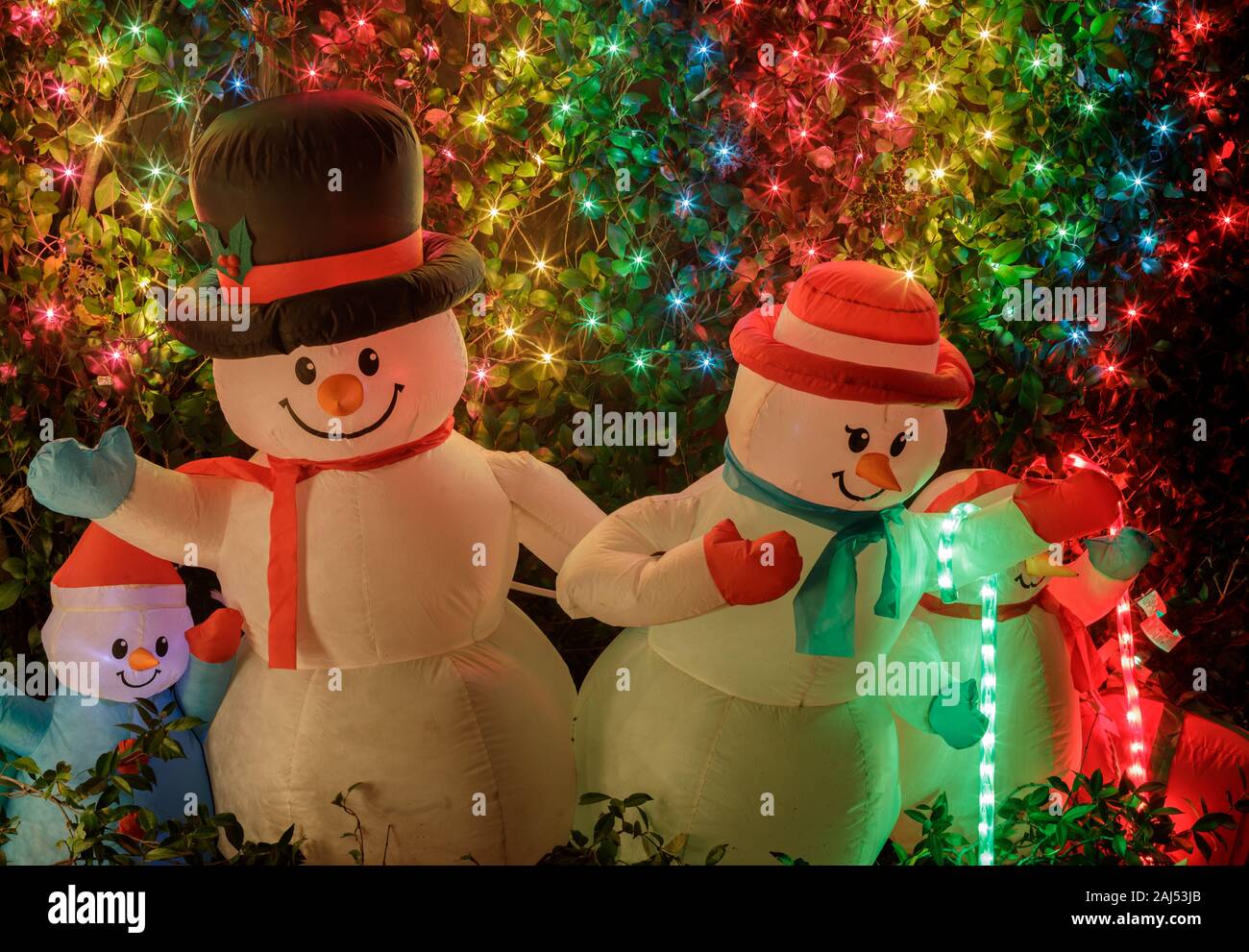 Snowman Family decorating front yard at night Stock Photo - Alamy