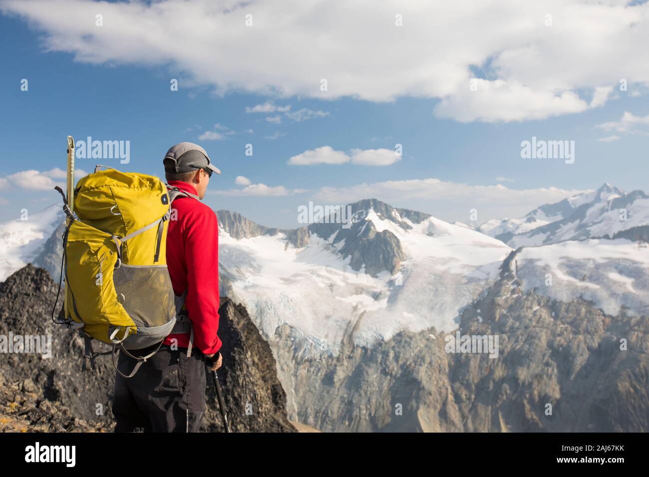 Side view of backpacker in mountains looking at glaciers Stock Photo ...