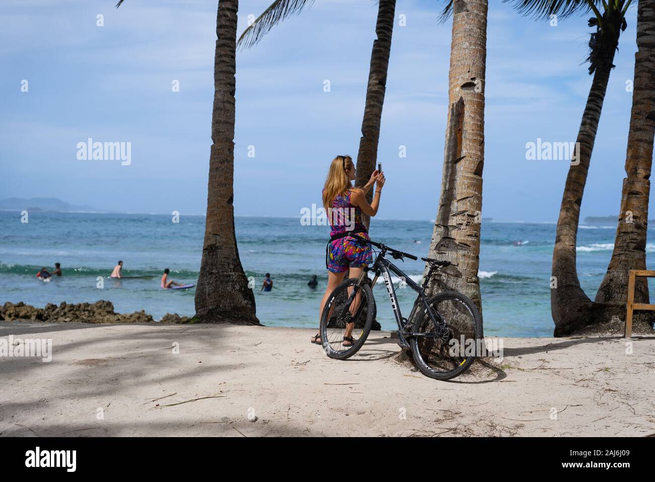 Beachfront & foreign visitor with a bicycle taking a photograph on a ...