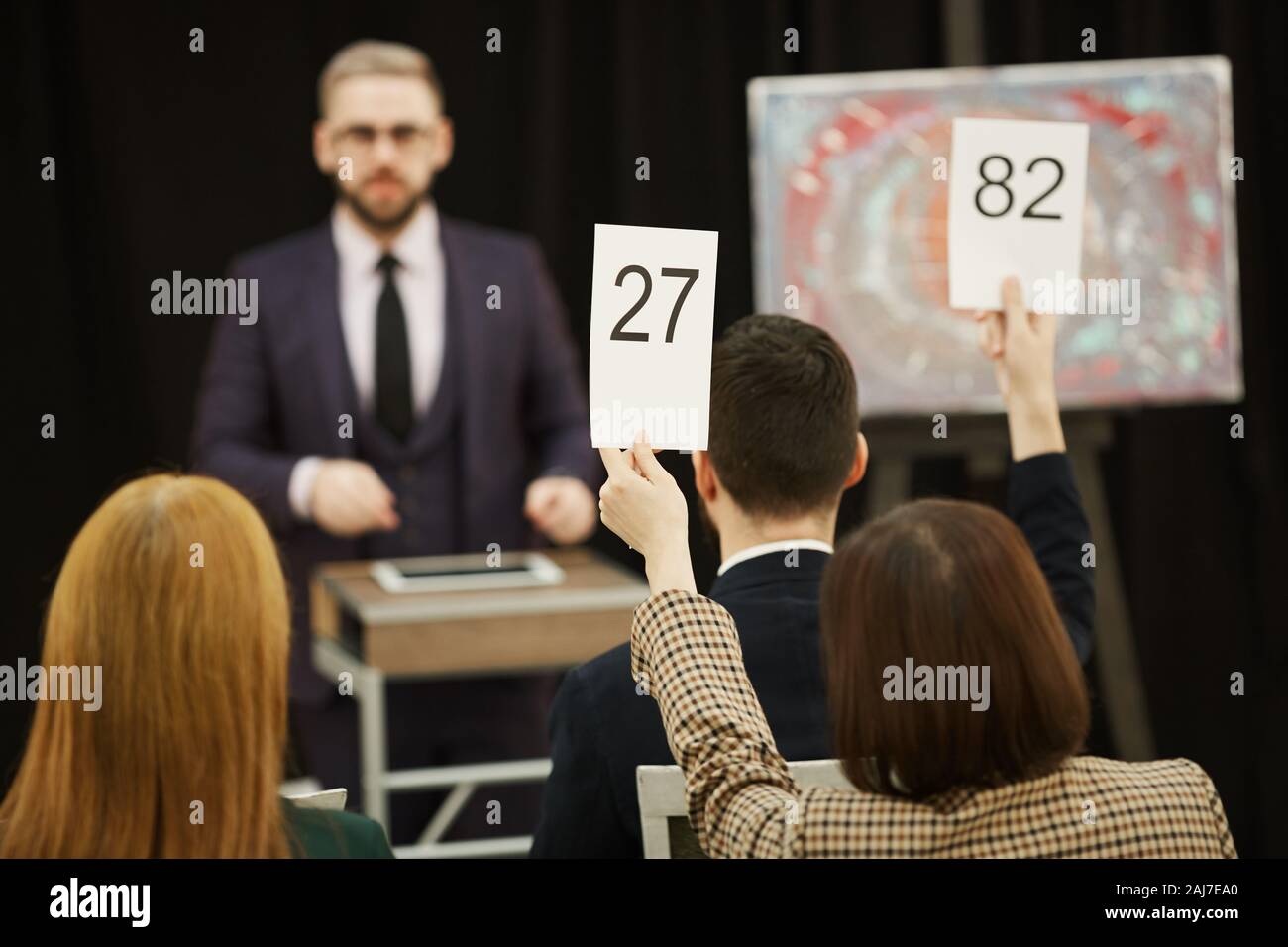 Rear view of group of people sitting and raising their signs with ...