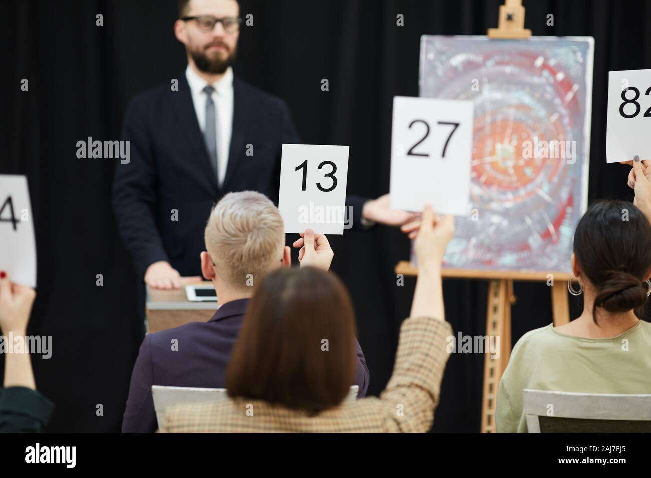 Rear view of group of business people sitting and raising signs with ...