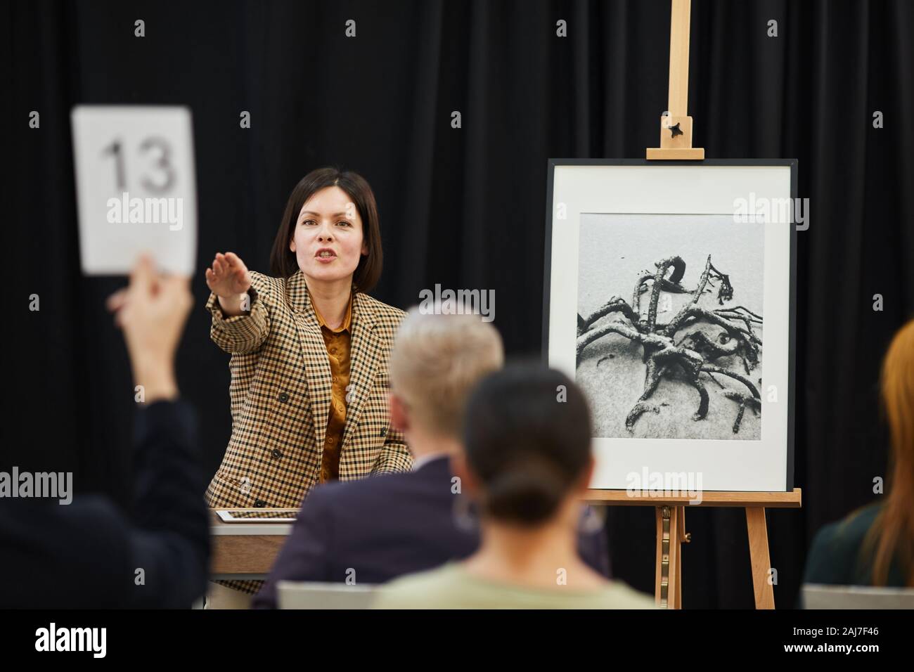 Businesswoman pointing at woman with sign and selling her the painting ...