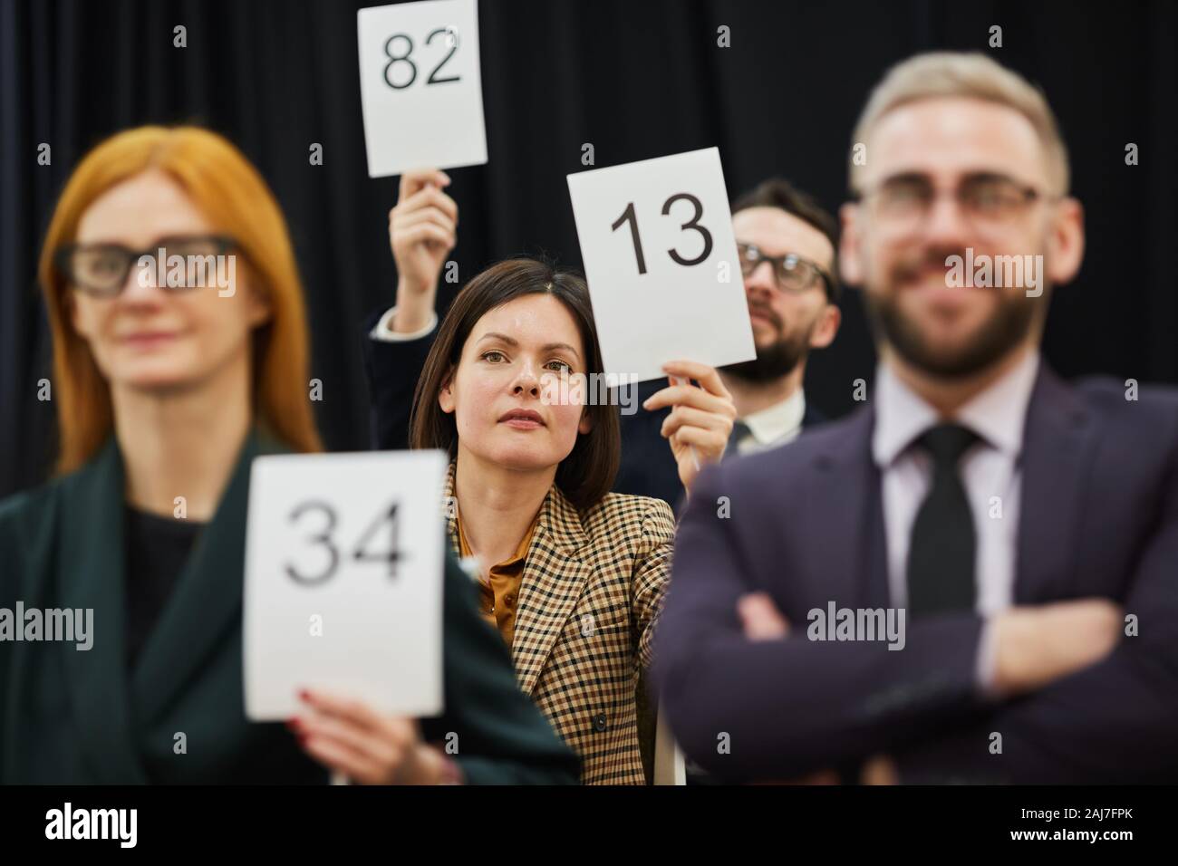 Group of people raising their signs and voting during business ...