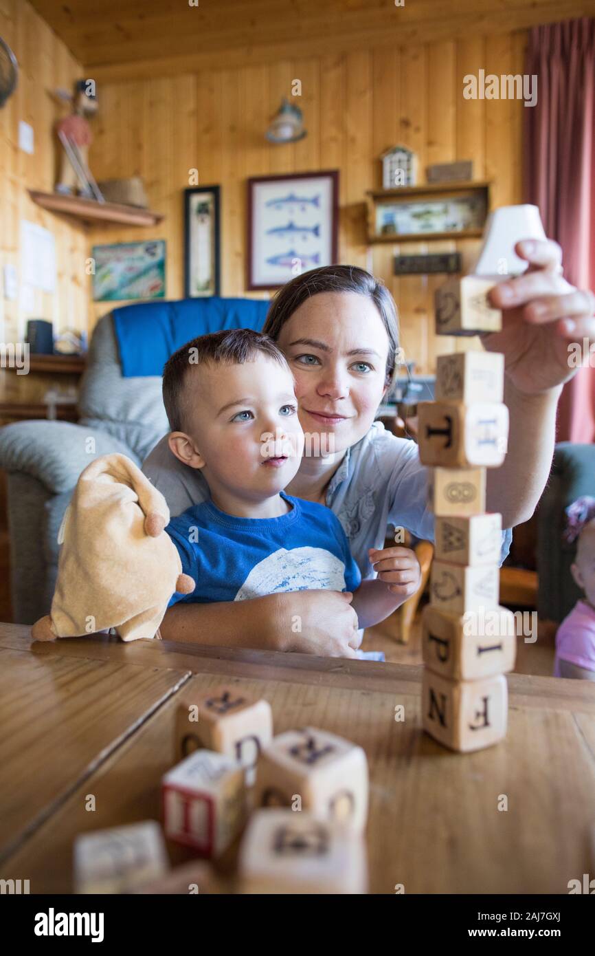 Mother helps son build block tower Stock Photo - Alamy