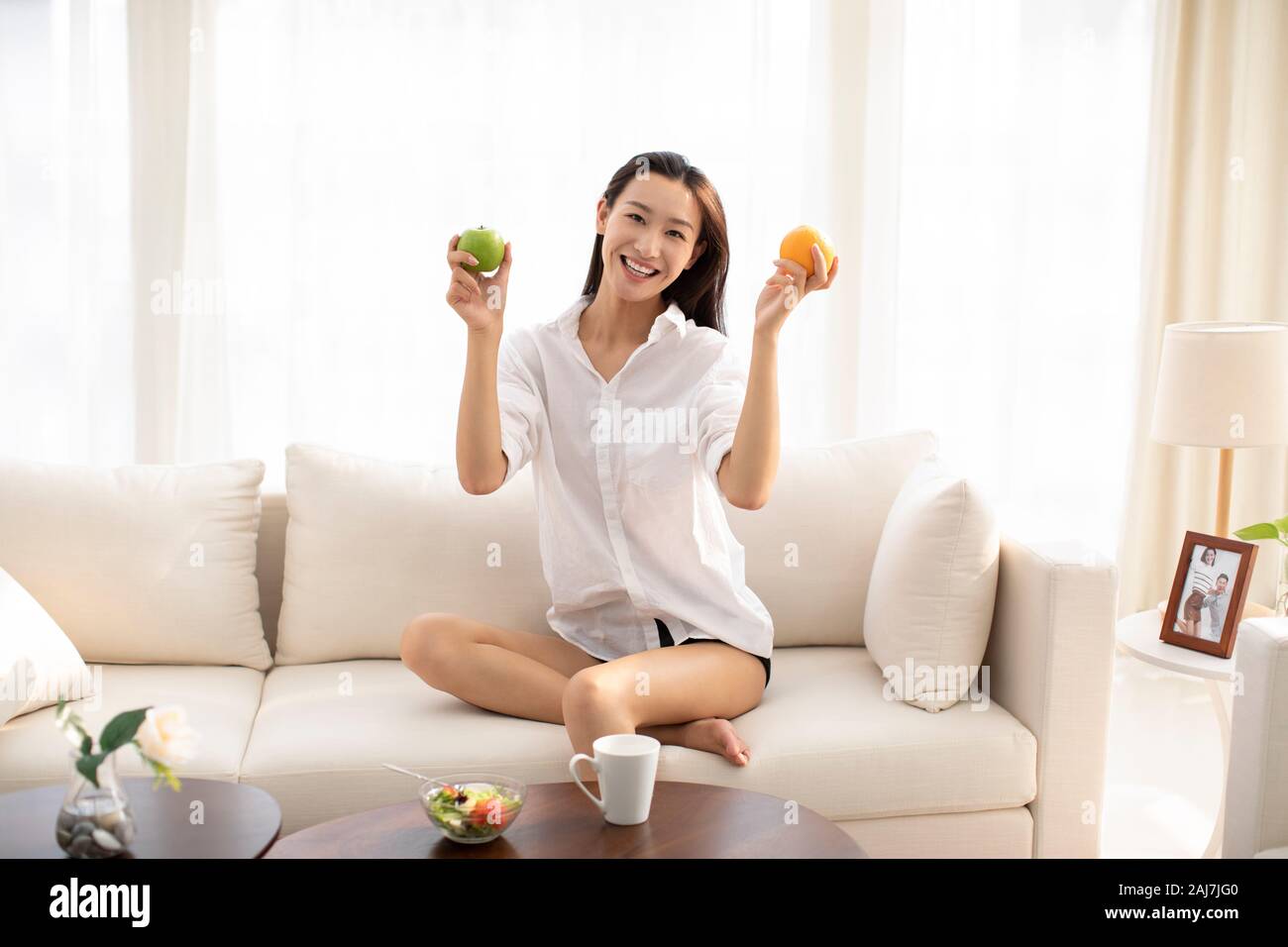 Young Chinese woman sitting on sofa Stock Photo - Alamy
