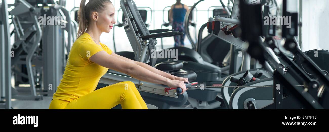 Side view of fit young woman using rowing machine in health club Stock ...