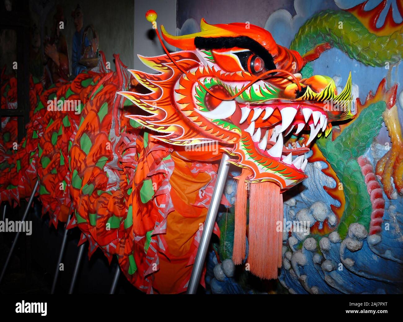 A dragon puppet with sticks on a temple's wall before Chinese new year ...