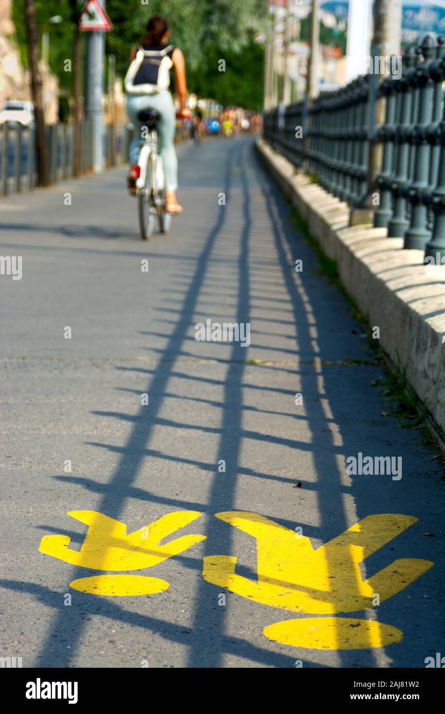 Yellow road marking for pedestrian on a sidewalk. Blurred bicyclist ...