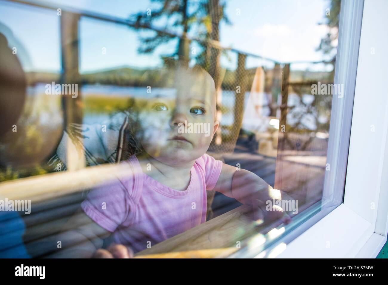Young girl looking out through window Stock Photo - Alamy