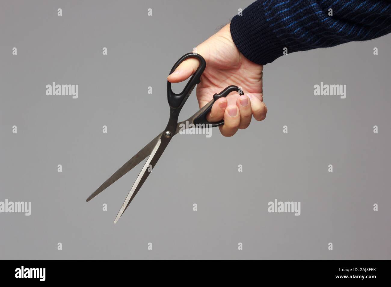 Large professional scissors in a person's hand, prepared to cut or trim ...