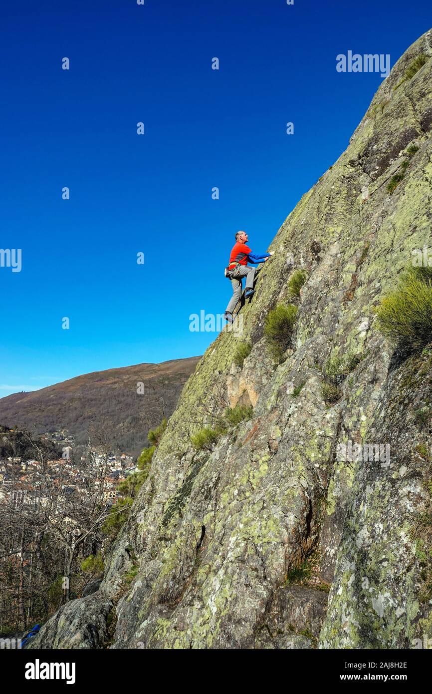 Male rock climber in red on cliff above Ax Les Thermes, Ariege, French ...